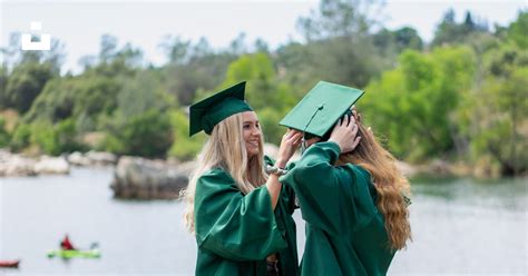 녹색 학술 드레스와 검은 박격포 보드를 입은 여자는 낮에 갈색 나무 통나무 위에 서 있다 사진 Unsplash의 무료 졸업 이미지