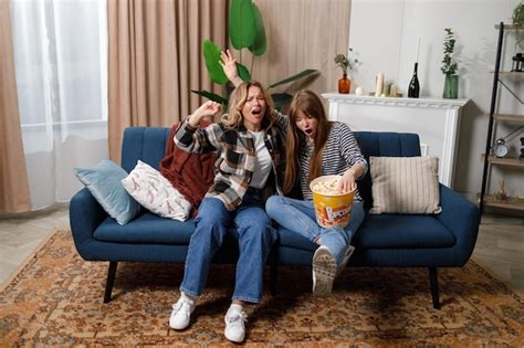 Premium Photo Crazy Mother And Adult Daughter Watching Tv While Have