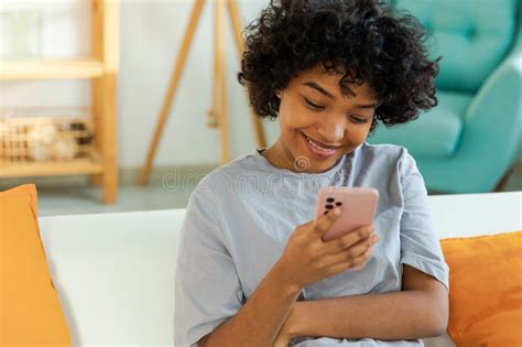 african girl holding smartphone touch screen typing scroll page at home
