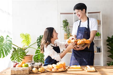 건강한 아침 식사를 만들기 위해 음식과 빵을 준비하는 아시아 남자와 여자 즐겁게 요리를 즐기고 매력적인 아내와 쾌활한 남편이 신선한 재료로 맛있는 식사를 준비하고 있습니다