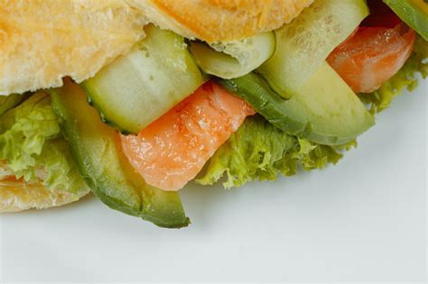 붉은 생선 아보카도 신선한 채소 검은 색 셰일 보드에 검은 색 셰일 보드에 아루굴라가 있는 크루아상 샌드위치가 검은 돌 배경 위에 있습니다 건강한 식품 개념 0명에 대한