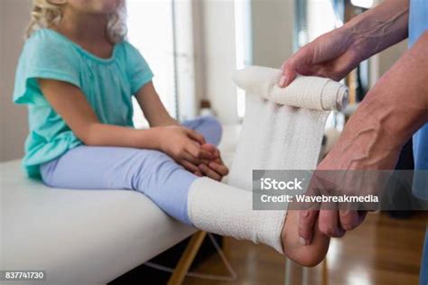 Fisioterapis Menempatkan Perban Pada Kaki Pasien Gadis Yang Terluka