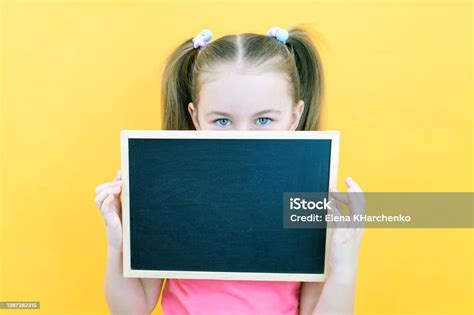 보드 시트를 들고 소녀 분필 보드와 귀여운 어린 소녀 노란색 배경입니다 복사 공간을 복사합니다 장소 공란에 대한 스톡 사진 및 기타 이미지 Istock