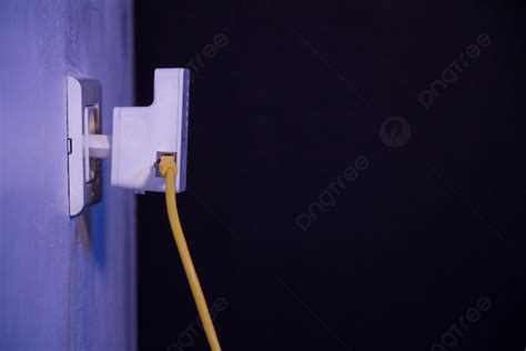 Wifi Extender In Electrical Socket On The Wall With Ethernet Cable Plugged In The Device Is In