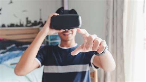 젊은 남자는 침실에서 가상 현실 고글을 입고 침실에 Vr 헤드셋을 사용 하 여 스마트 폰 3차원 형태에 대한 스톡 사진 및 기타