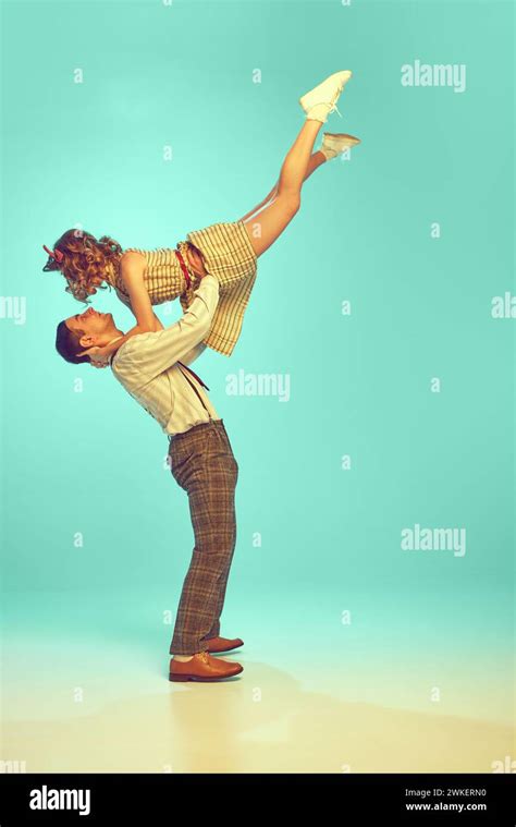 Dynamic Portrait Of Happy Couple Performing Lively Swing Dance Moves In Motion Against Gradient