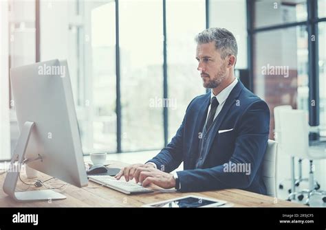 No Task He Cant Complete Without Technology A Mature Businessman Using A Computer At His Desk