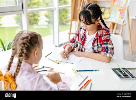Multiracial Girls Drawing During Class In Art School Indoors Stock