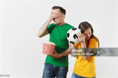 젊은 부부 여자 남자 노란색 녹색 티셔츠 응원 팝콘 흰색 배경에 고립의 축구 공 통 지원 팀에서 축구 팬 들을 깜짝 놀라게 했다 스포츠 가족 여가 라이프 스타일 개념