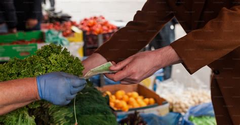갈색 코트와 파란 장갑을 낀 사람이 다른 사람에게 당근을 건네고 있다 사진 Unsplash의 시장 이미지