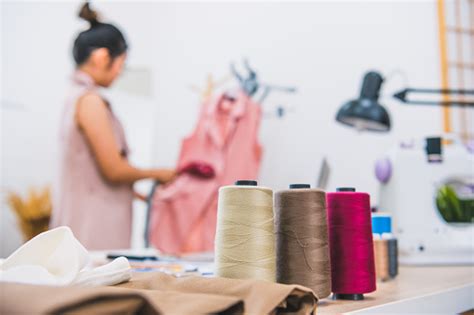 워크샵 스튜디오에서 패션 디자이너 배경과 다채로운 스레드의 클로즈업 새로운 천 디자인 컬렉션을 만드는 세련된 패셔니 스타 여성