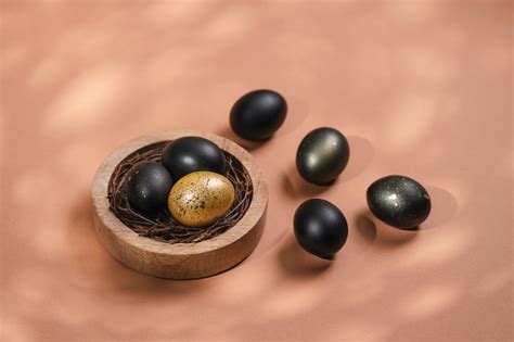 계란은 베이지색 배경에 검은색과 금색으로 칠해져 있습니다 3 개의 알을 담고있는 둥지 최소한의 부활절 개념 0명에 대한 스톡