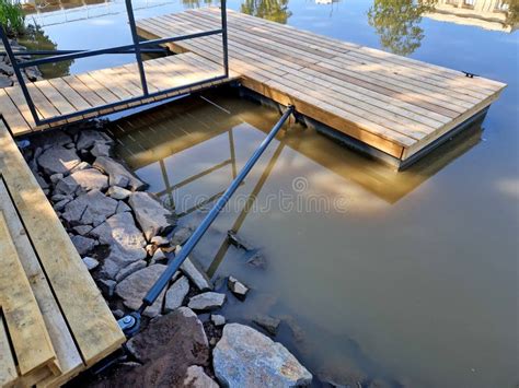 A Floating Jetty For Mooring Ships Is Fixed With Metal Rods On Hinges Wooden Stairs Are Benches