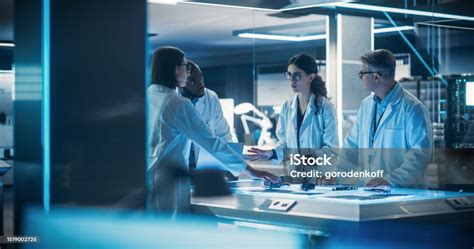 다양한 산업용 로봇 전문가 팀이 바이오닉 로봇의 개발 부품이 있는 테이블 주위에 모였습니다 노트북 컴퓨터를 사용하여 인공 손