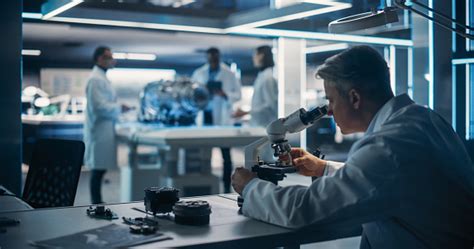 다양한 다민족 산업 엔지니어 팀이 프로토타입 터빈 엔진을 들고 테이블 주위에 모였습니다 과학자들은 태블릿 컴퓨터와 현미경을