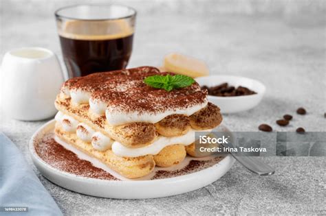 전통적인 이탈리아 레이어드 디저트 티라미수 마스카포네 크림 비스킷을 흰색 접시에 담고 회색 콘크리트 배경에 커피 한 잔을 담고 있다 0명에 대한 스톡 사진 및 기타 이미지