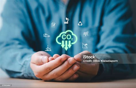 환경 아이콘이 있는 탄소 감축 표지판을 들고 있는 사업가는 녹색 공장 탄소 발자국을 위한 전기 자동차 재활용 기후 변화로 인한 지구 온난화를 제한하기 위한 탄소 배출권 등을