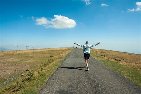 두 남자가 도로에 남겨진 차를 쫓고 있습니다 팔을 뻗은 남자는 휴가 중 산에서 여름에 자동차와 달리기 친구를 따라 잡고 싶어