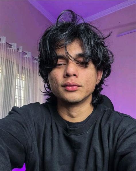 A Man With Long Black Hair Is Looking At The Camera And Has His Eyes Closed