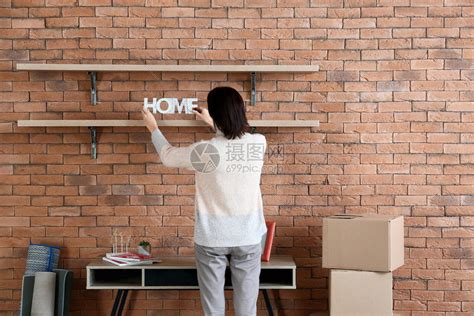搬进新公寓后女人把装饰放在架子上高清图片下载 正版图片507483436 摄图网