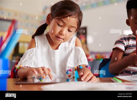 Élève de sexe féminin à l école primaire à l aide de dessin digital Tablet In Classroom Photo
