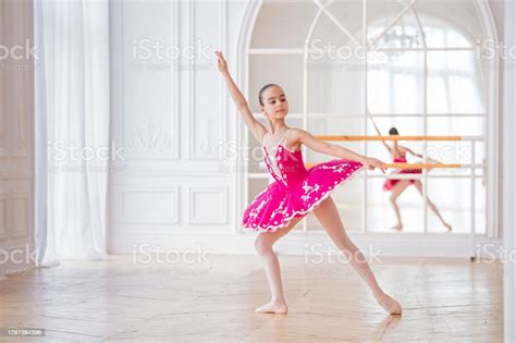 밝은 투투를 입은 작은 발레리나는 큰 조명 홀 한가운데서 뾰족한 지점에 서 있습니다 8 9 살에 대한 스톡 사진 및 기타 이미지 8 9 살 거울 건강한 생활방식