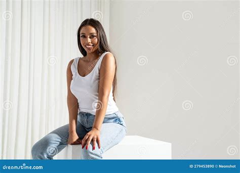 Cheerful Young Woman In Casual Outfit In White Tank Top And Jeans