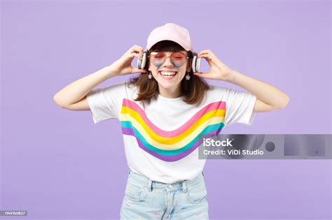 생생한 옷에 웃는 십 대 소녀 안경은 보라색 파스텔 배경에 고립 눈을 폐쇄 유지 헤드폰 음악을 듣습니다 사람들은 진심으로 감정 라이프 스타일 개념입니다 복사 공간을 모의