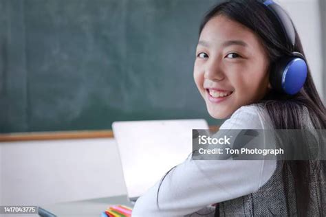 교실에서 컴퓨터 노트북을 사용하여 헤드폰을 착용하는 행복한 학생 칠판 앞에 앉아있는 학생 학교 하루 개념 10 11세에 대한