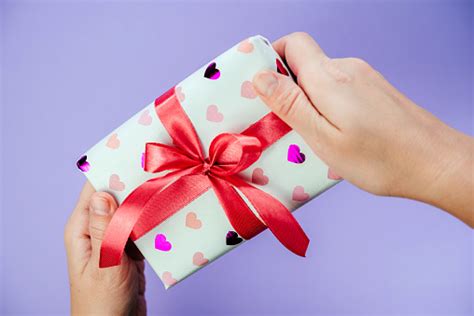 보라색 배경에 빨간 리본 리본 리본하트 패턴 종이에 싸여 선물 상자를 들고 있는 손 2월에 대한 스톡 사진 및 기타 이미지 2월 긍정적인 감정 표현 나비매듭 Istock