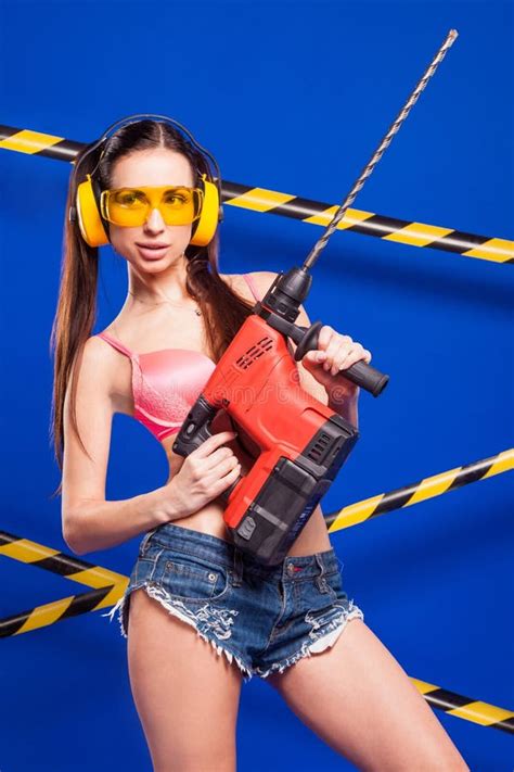 Brunette Builder On A Blue Background With An Electric Tool In The Hands Of Stock Photo Image