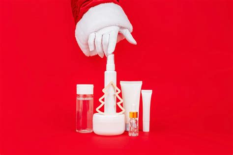 산타의 손은 일 크림 화장품 오일 붉은 배경에 아이 크림을 터치합니다 모형 스타일의 브랜드가 없는 병 천연 화장품 컨셉 겨울에 대한 스톡 사진 및 기타 이미지 Istock