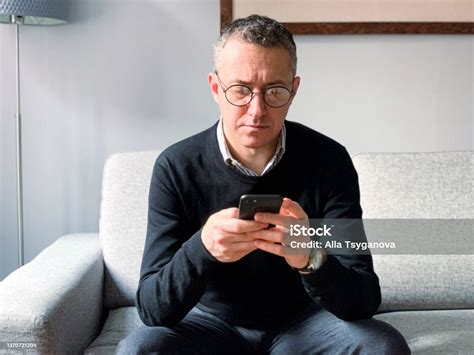 중년 남성은 사무실에 가서 고객과 이야기하기 전에 아침에 집에서 소파에 앉아 있습니다 40 44세에 대한 스톡 사진 및 기타 이미지 40 44세 Brand Name