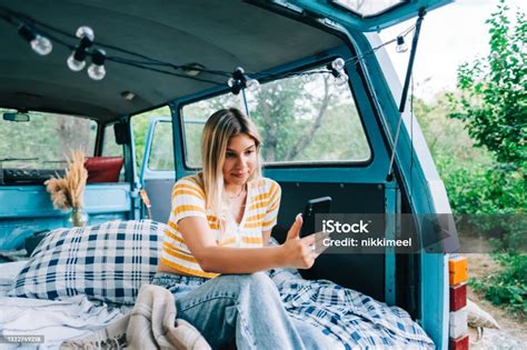 밴에 앉아 휴대 전화를 사용하여 젊은 여성의 초상화 자연에서 야외 여름을 즐기는 여행 컨셉 Brand Name Smart Phone에 대한 스톡 사진 및 기타 이미지