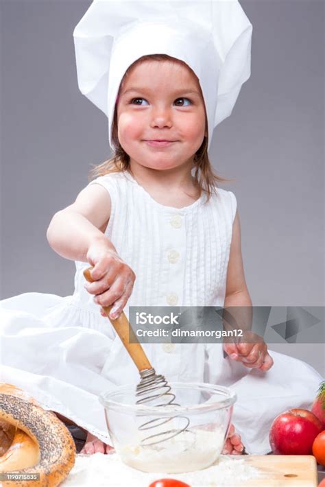 식품 개념 스튜디오 환경에서 거품기로 밀가루 계란 및 야채를 혼합하는 요리 유니폼을 입은 기쁘고 웃는 코카서스 소녀 세로 이미지 2 3 살에 대한 스톡 사진 및 기타 이미지