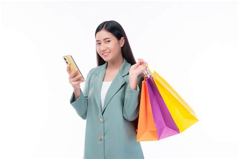 화려한 쇼핑백과 스마트 폰을 들고있는 젊은 아시아 여성 행복하게 미소 짓고 흰색 배경에 고립 온라인 쇼핑 디지털 결제 및 현대 라이프 스타일 소매 경험의 개념 25 29세에