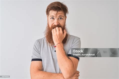 젊은 빨간 머리 아일랜드 남자 회색 폴로 고립 된 흰색 배경 위에 서 서 스트레스와 긴장 입 물고 손톱에 손으로 불안 문제 감정에 대한 스톡 사진 및 기타 이미지 Istock
