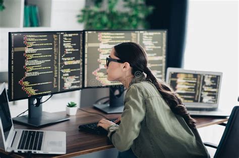 Young Female Programmer Working On Multiple Monitors In Casual Attire