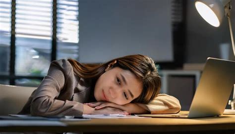 An Employee Showing Signs Of Burnout Slumped Over Their Desk With A