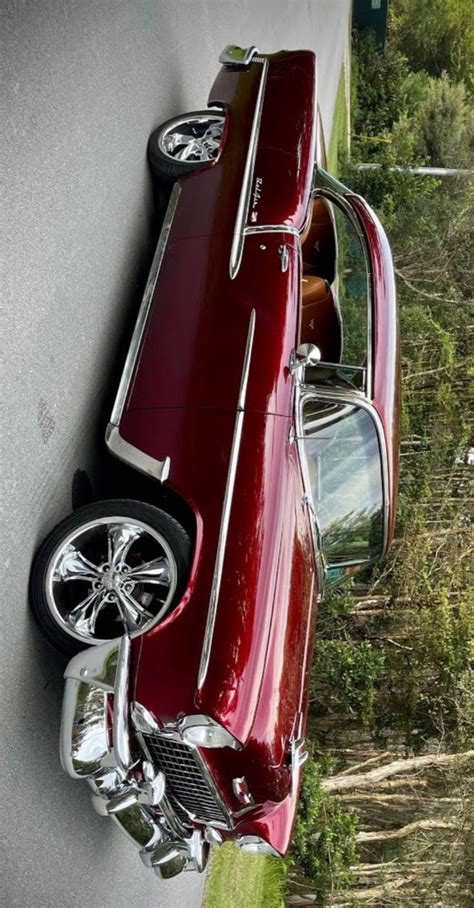 An Old Red Car Is Parked On The Side Of The Road