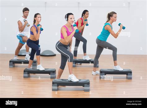 Fitness Class Performing Step Aerobics Exercise With Dumbbells Stock