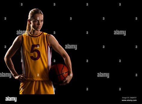 Female Basketball Player Shows Determination In Uniform On Black
