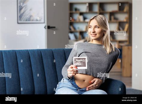 Photo Of A Pregnant Woman At Home Sitting On Couch Near Beautiful