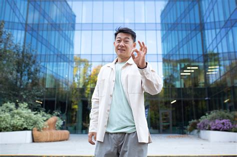 미소 짓고 자신감 넘치는 젊은 아시아 남성이 사무실 건물 밖에 서서 카메라를 향해 손으로 오케이 사인을 보여주는 초상화 35 39세에 대한 스톡 사진 및 기타 이미지