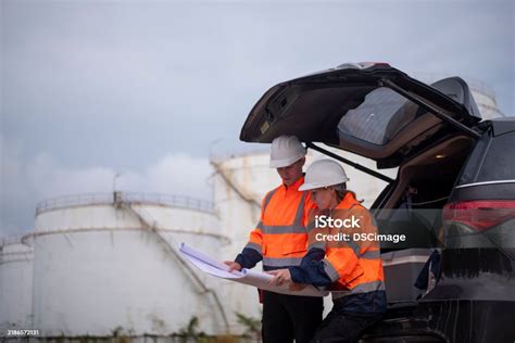 안전모를 포함한 안전 장비를 착용한 엔지니어가 대형 청사진 태블릿을 조사하고 산업 시설에 서 있는 가스 또는 정유 공장에 종사하는 작업에 종사하는 높은 안전 기준 개념이