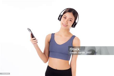 초상화 젊은 아시아 여자 운동복 착용 헤드폰 듣기 음악 스마트 폰 절연 된 흰색 배경 헤드폰을 착용 한 여자 스마트 폰 스포츠 개념으로 휴식 오디오를 듣고 있습니다
