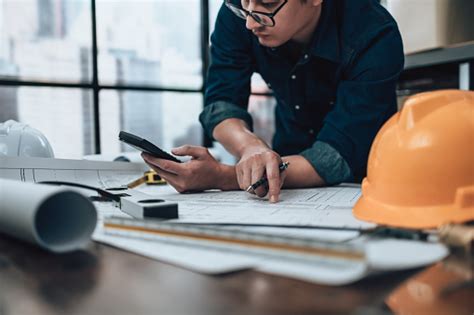 사무실 책상과 삼각형 눈금자 안전 안경 나침반 블루프린트의 버니어 캘리퍼에서 도면 검사 및 프레스 계산기로 작업하는 엔지니어링 엔지니어 건축가 산업 및 공장 개념 35 39