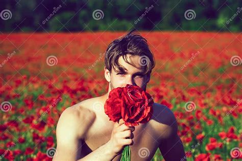 сексуально голый молодой человек держит букет красного мака цветок