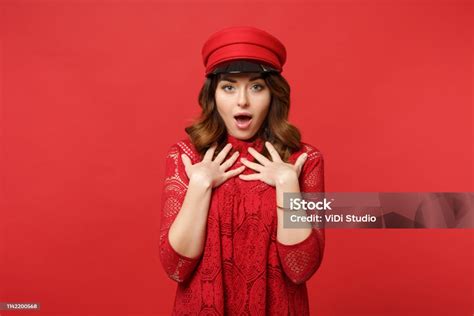 놀란 젊은 여자의 초상화 레이스 드레스와 모자는 입을 열어 밝은 빨간색 벽 배경에 고립 된 가슴에 손을 넣어 사람들은 진심으로 감정 라이프 스타일 개념입니다 복사 공간을