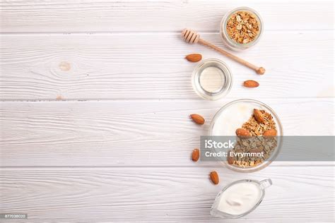 우유와 백색 나무 테이블 평면도에 그리스 요구르트와 아몬드 캐슈 너트 건조 과일 그 라 놀라 Superfood 건포도 유리에
